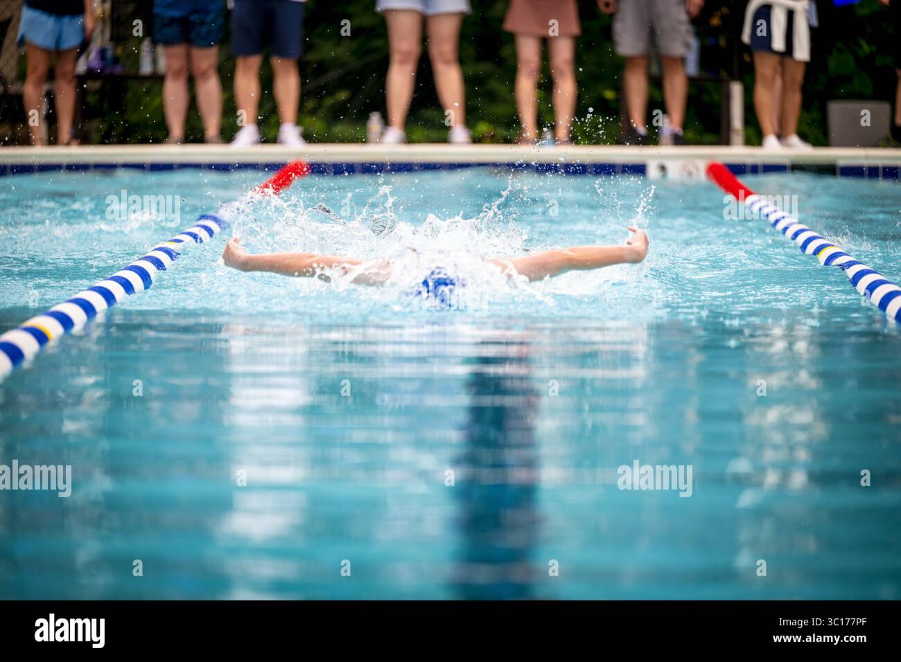 A youth swimmer competes in the butterfly stroke during a summer ...