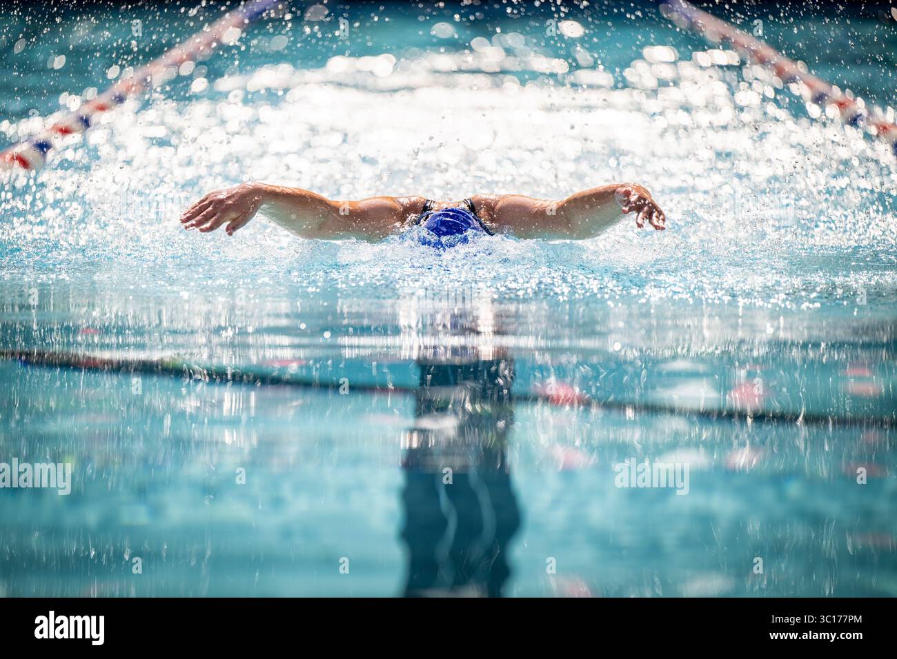 A youth swimmer competes in the butterfly stroke during a summer ...