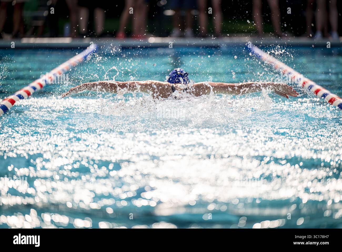 A youth swimmer competes in the butterfly stroke during a summer ...