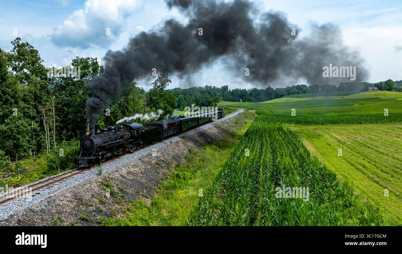 A historic steam locomotive chugs along a railway, emitting black smoke ...