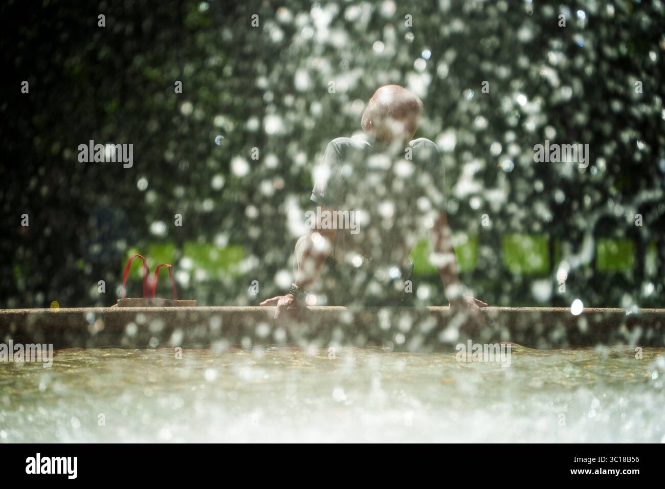 22 July 2025, Hesse, Frankfurt/Main: A man enjoys the sun at the Lucae ...
