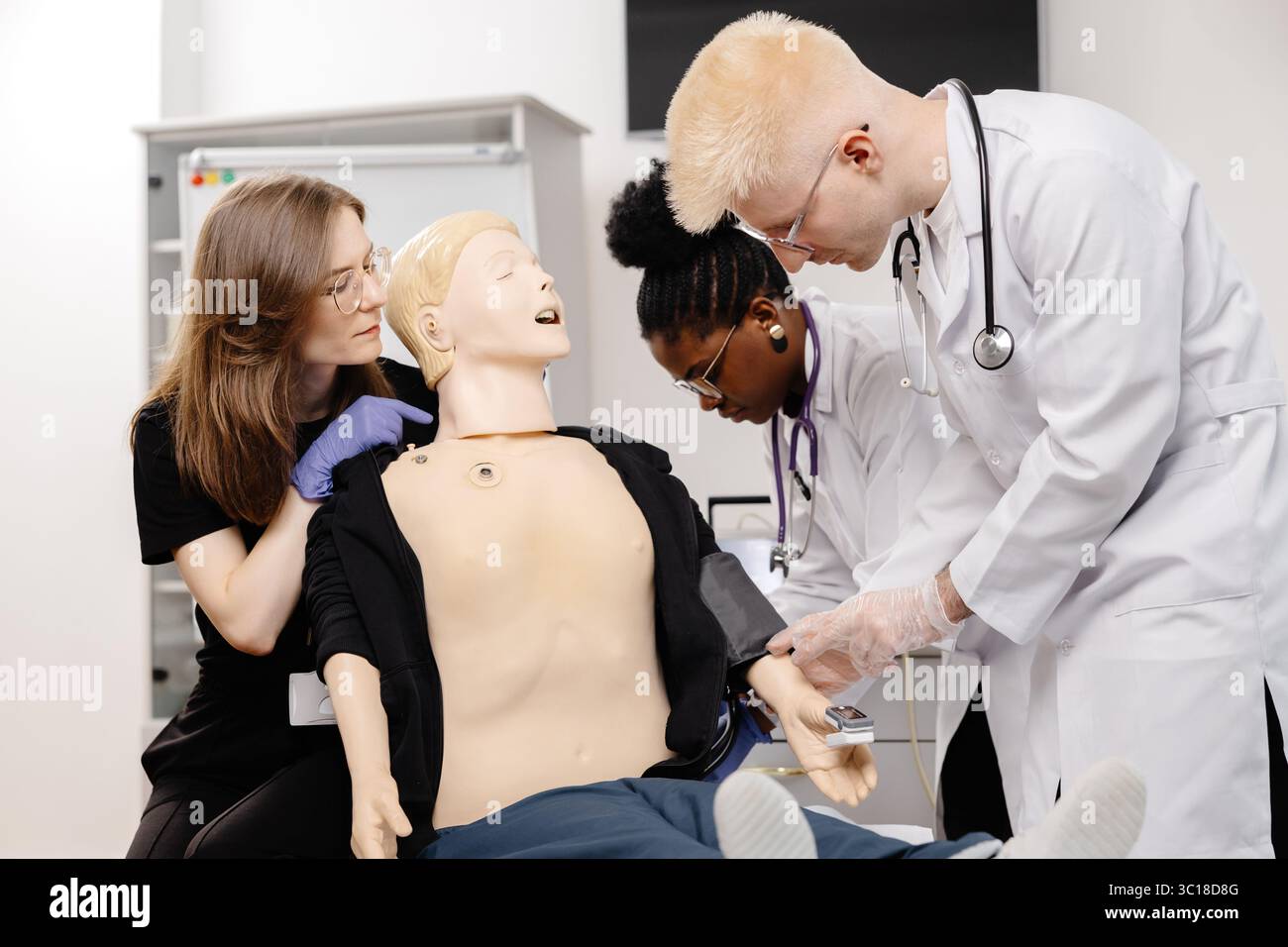 Group of diverse medical students examining anatomical model using stethoscope during practice ...