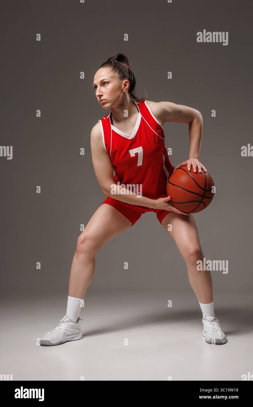 Confident female basketball athlete in red uniform ready for defense ...