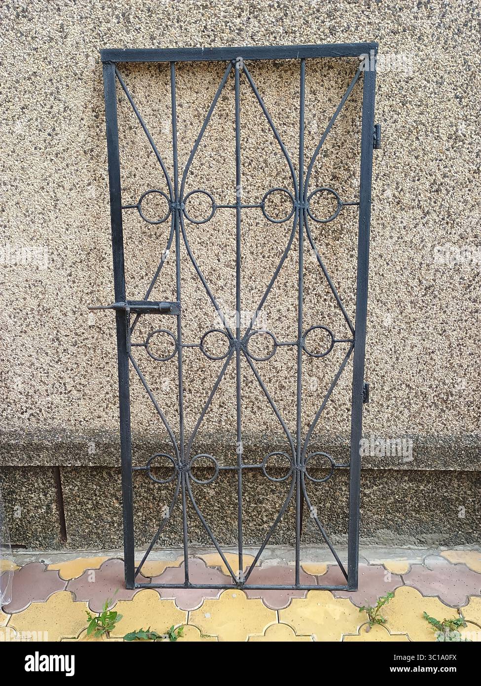 A dark blue wrought iron window grille is mounted securely on a rough ...