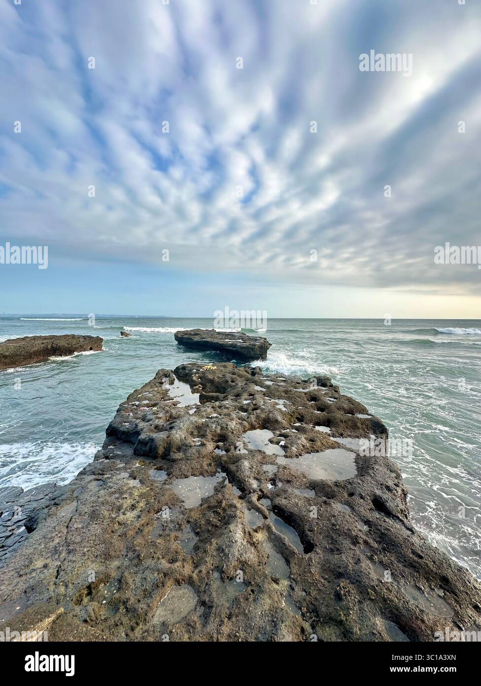 Rocky Coastline with Calm Sea and Partly Cloudy Sky Stock Photo - Alamy