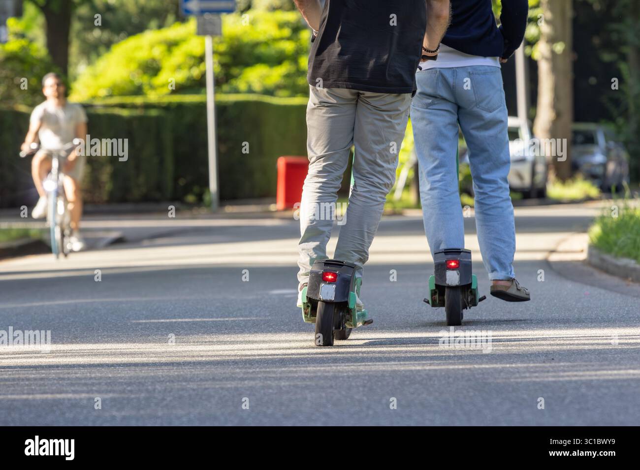 two men on electric scooters ride on the street Stock Photo - Alamy