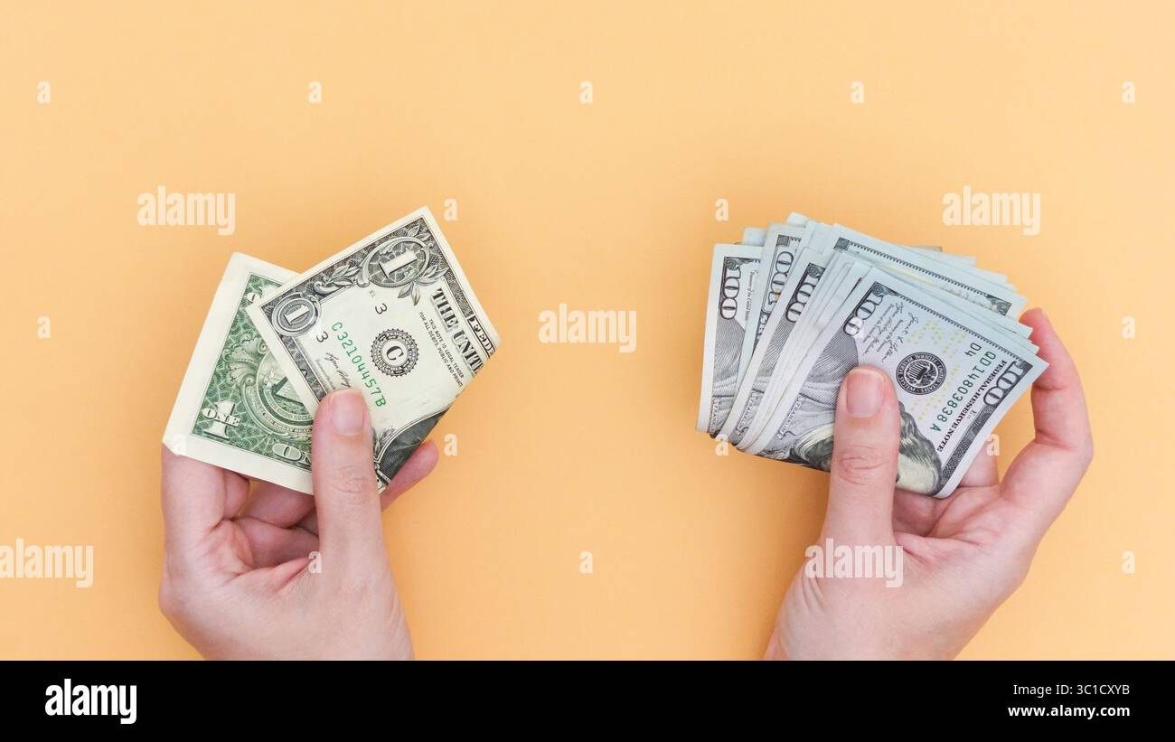 An overhead shot shows two hands one grasping a few dollar bills and ...