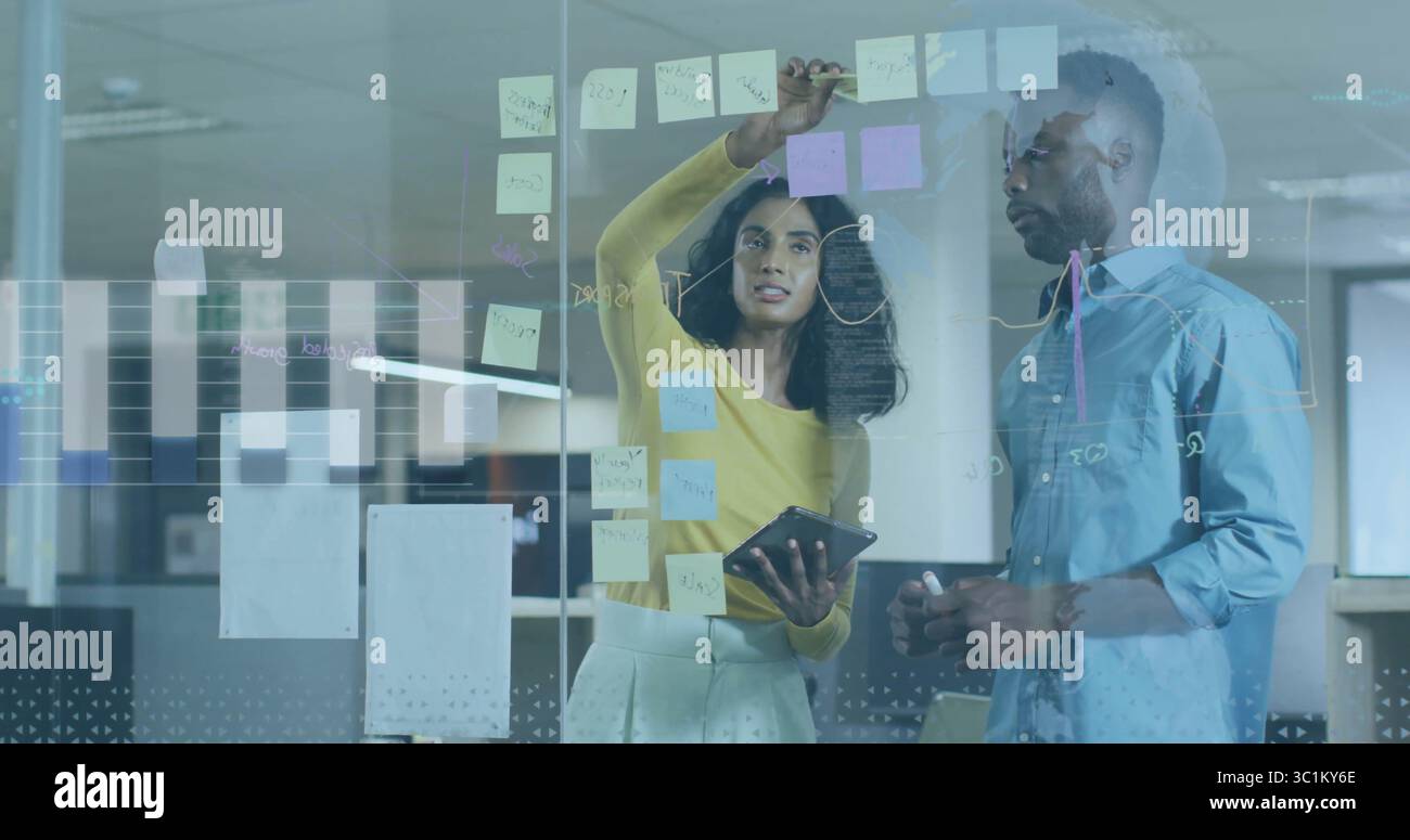 Placing sticky note, brainstorming plan in business attire on glass ...