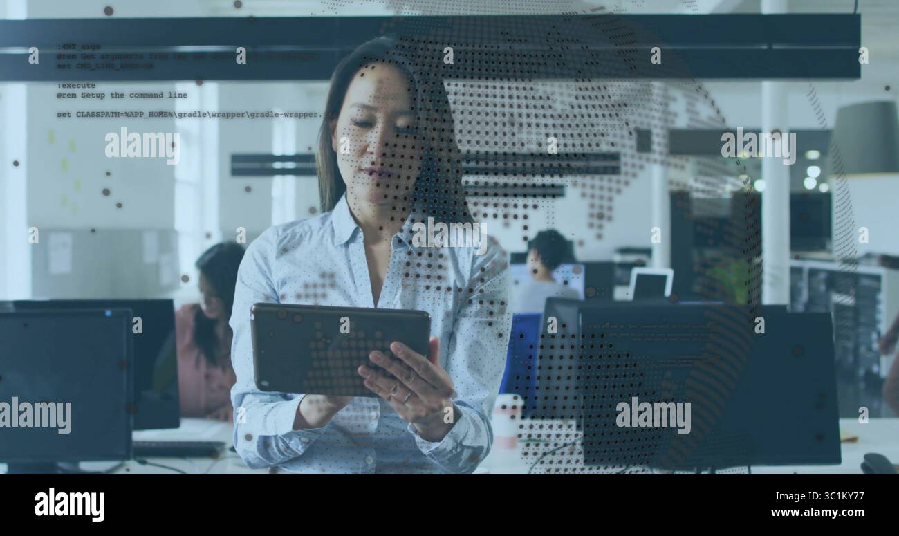 Standing Asian project manager holding tablet in open plan office, with ...