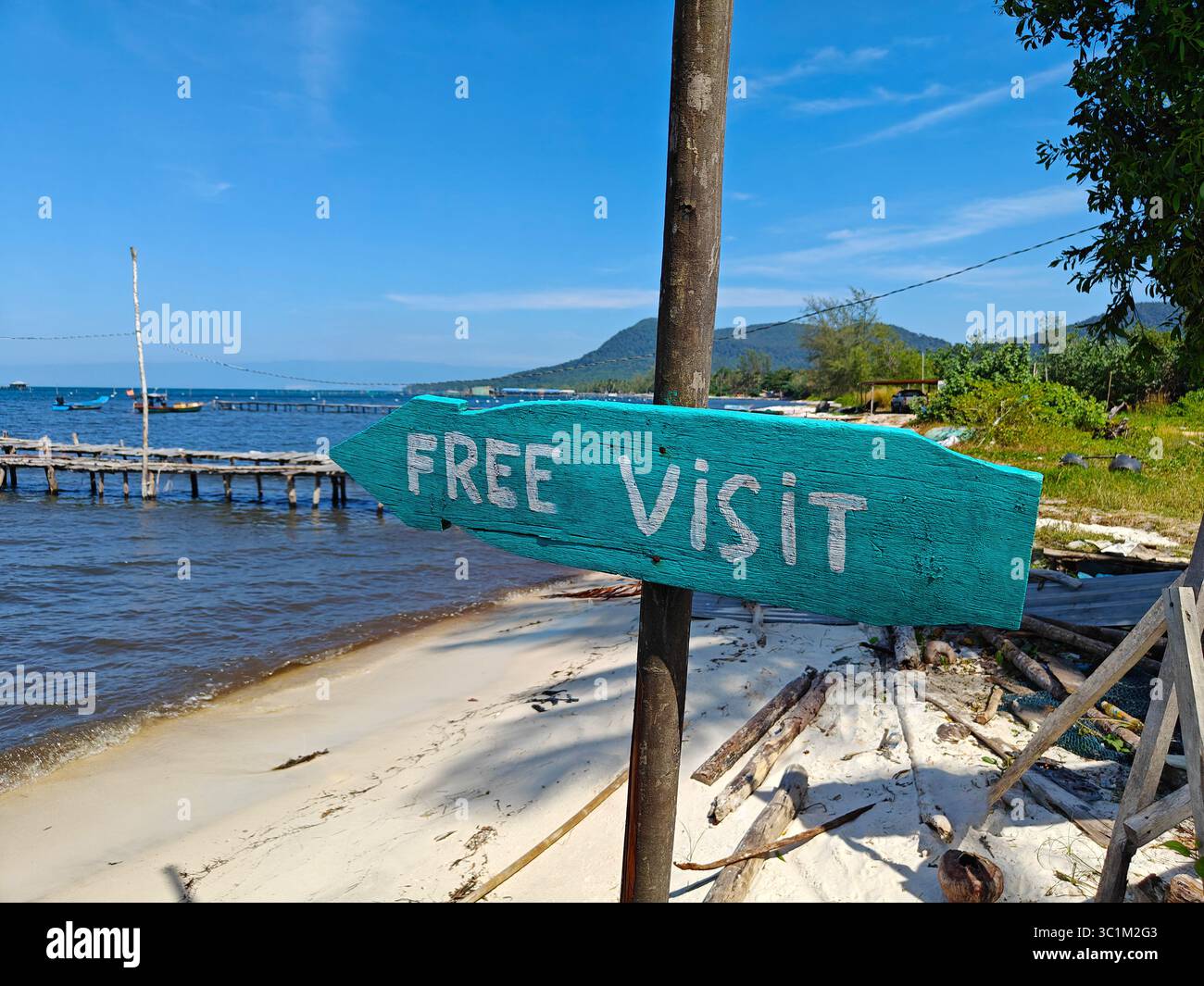 Wooden turquoise sign with FREE VISIT written in white points toward a ...