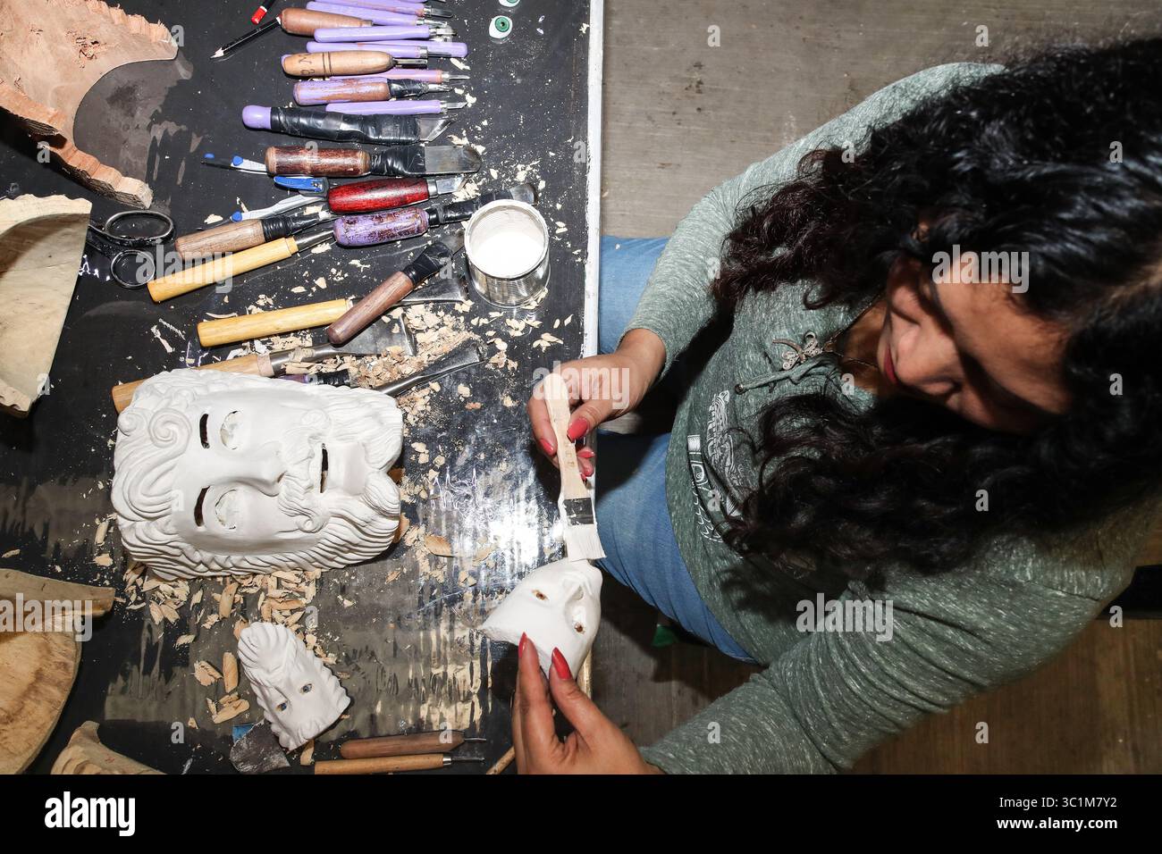 Artisan Elsa Padilla puts down a base of paint on a wooden mask during ...