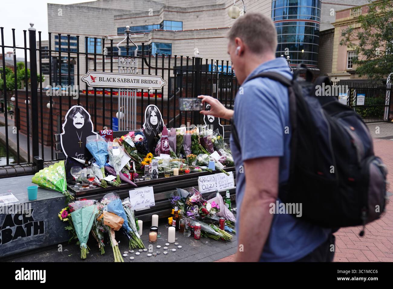 A man takes a picture of floral tributes left on the Black Sabbath ...