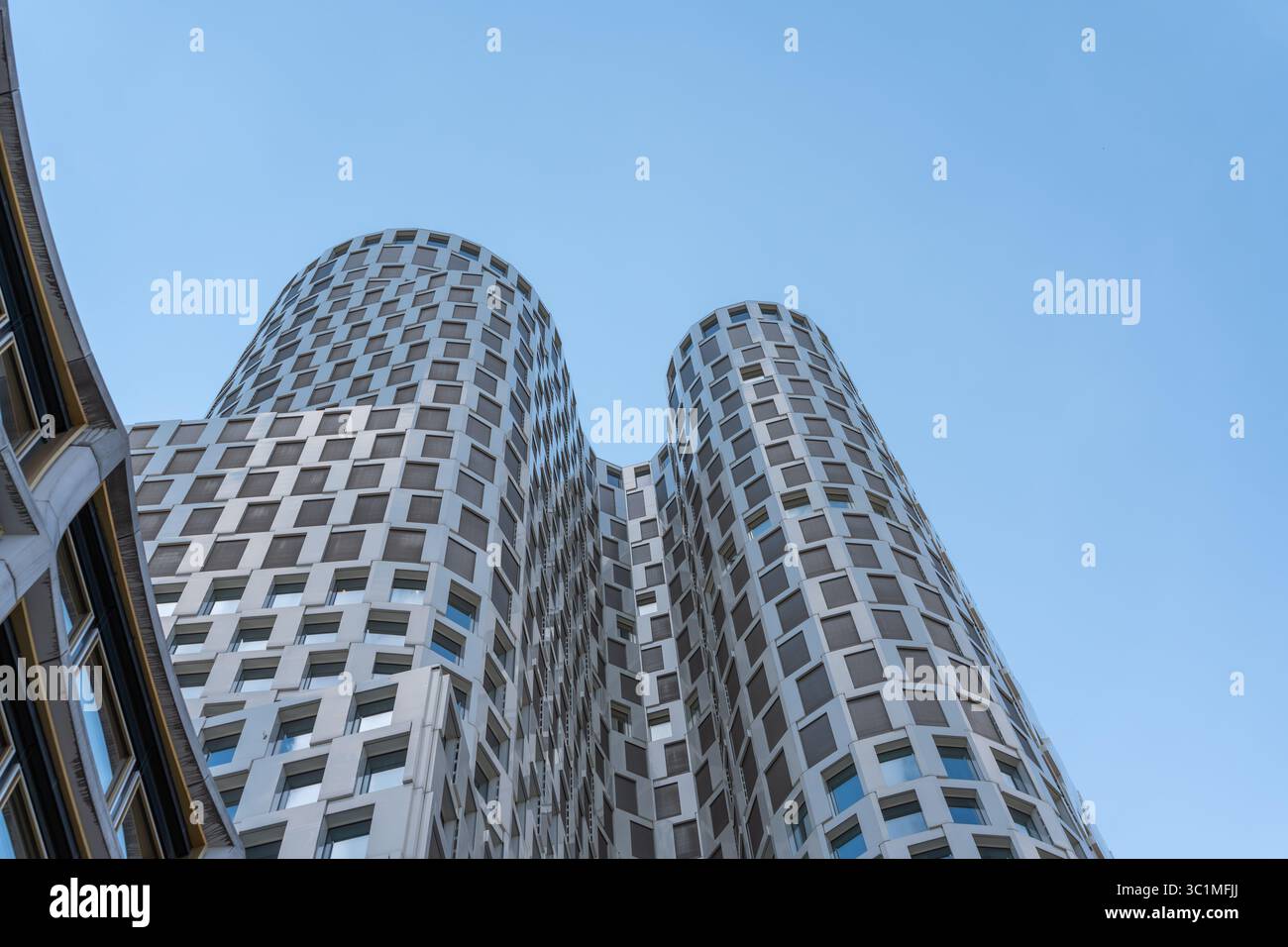 Two modern towers with undulating window structures rise into the blue ...