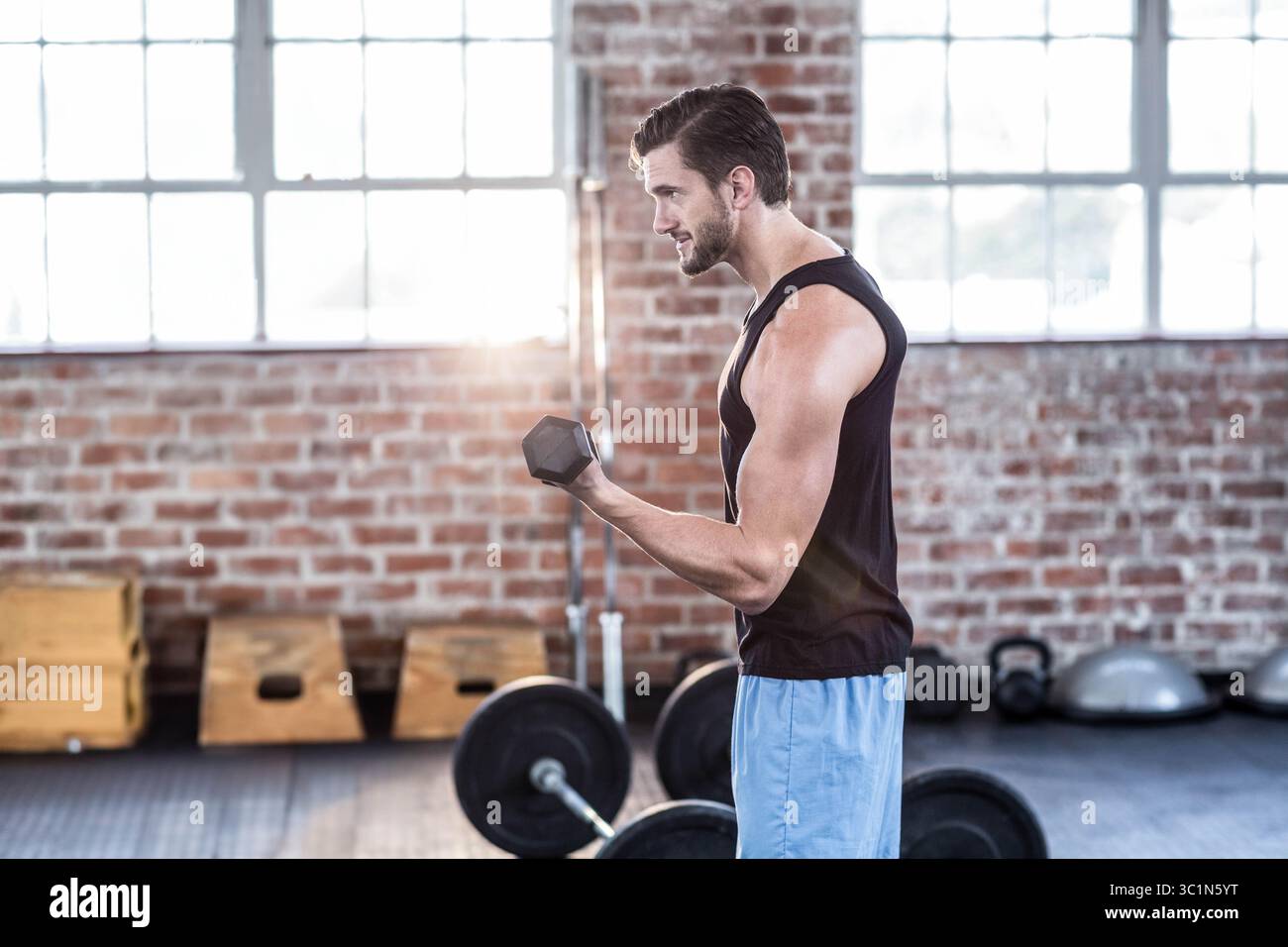 Male lifting hexagonal dumbbell and curling biceps while wearing ...