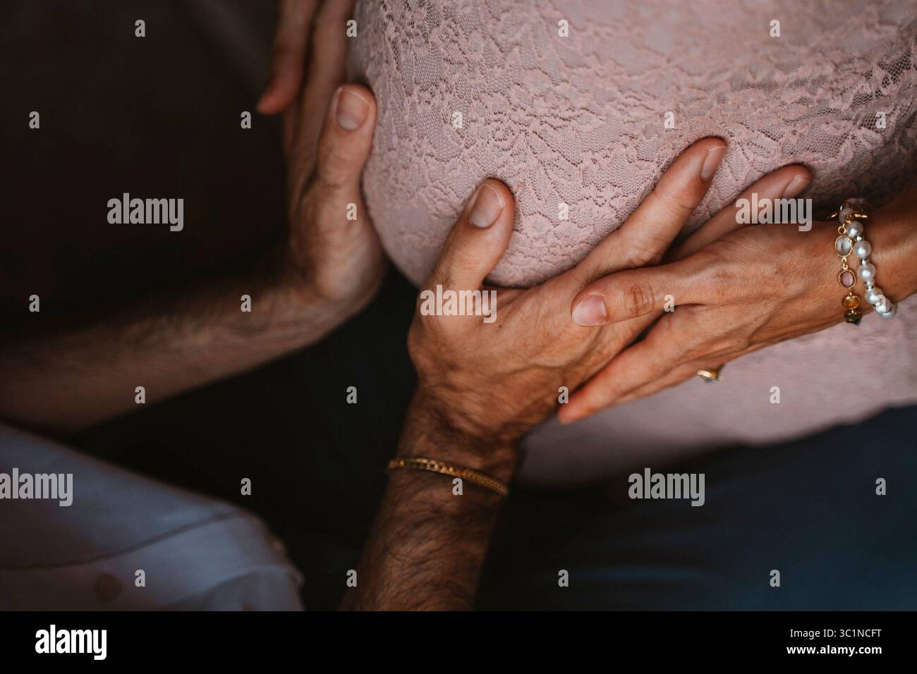 Close-up image of hands tenderly holding a pregnant belly, expressing ...