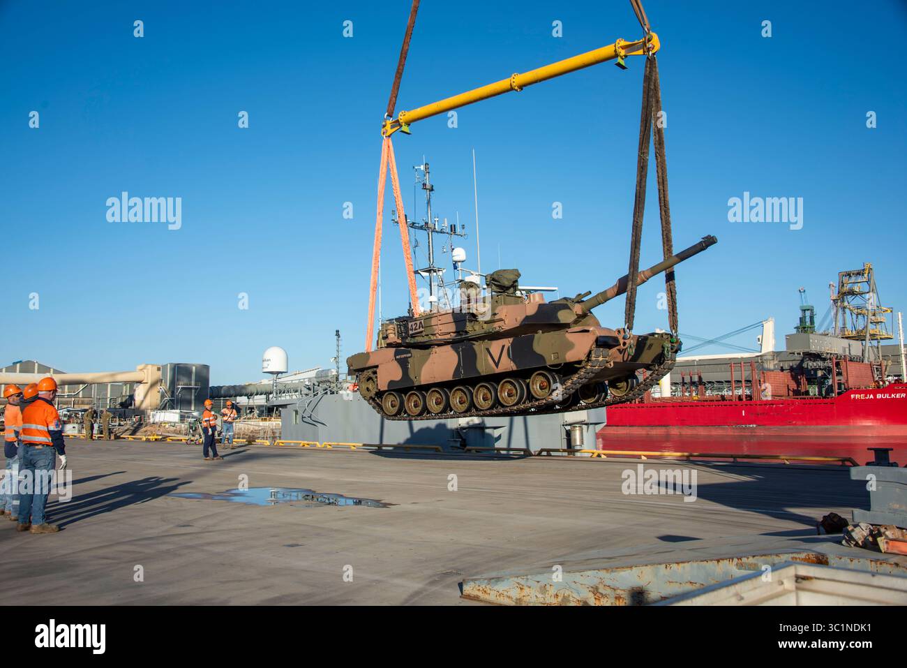 An Australian tank is lifted to be placed on a transport ship during ...