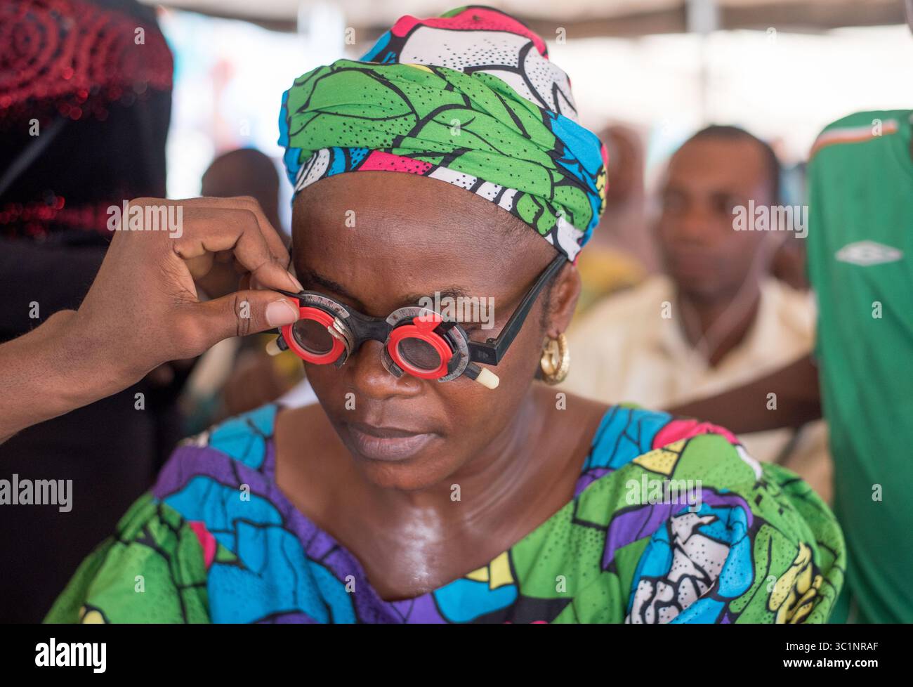 A woman wears medical glasses to test her vision during a medical ...