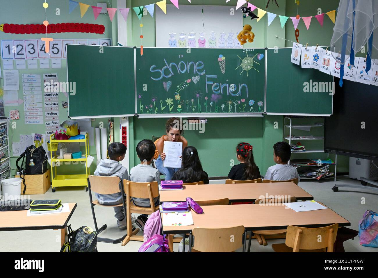 23 July 2025, Berlin: Teacher Vanessa Freigang hands out report cards ...