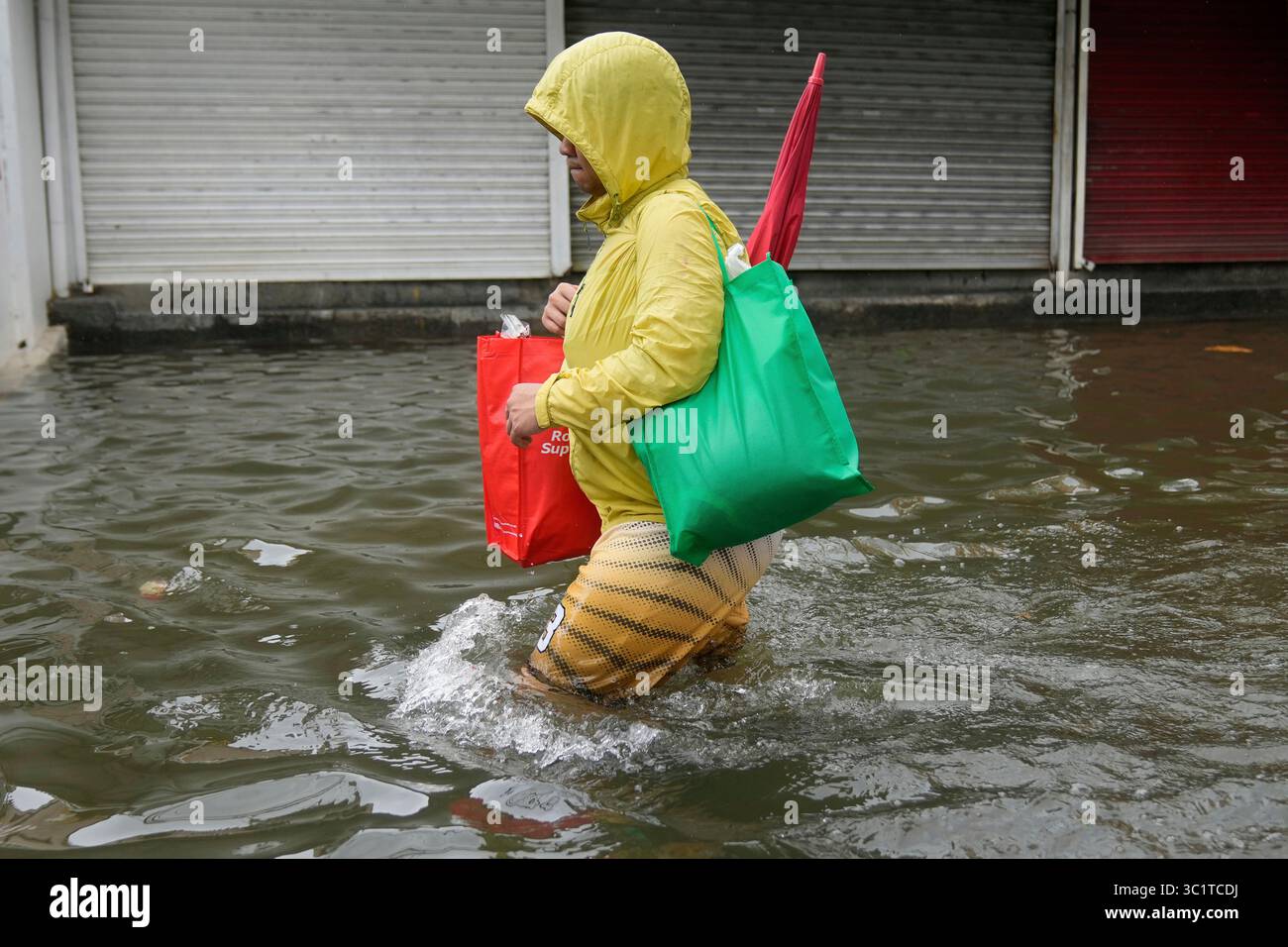 A resident walks through flood water after intense rainfall caused by ...