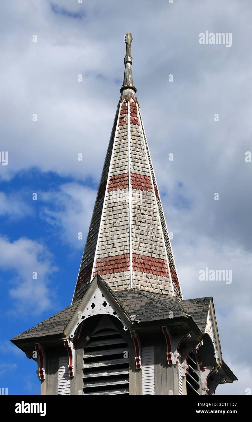 Blue sky and clouds surround the octagonal, wooden shingled, spire of ...