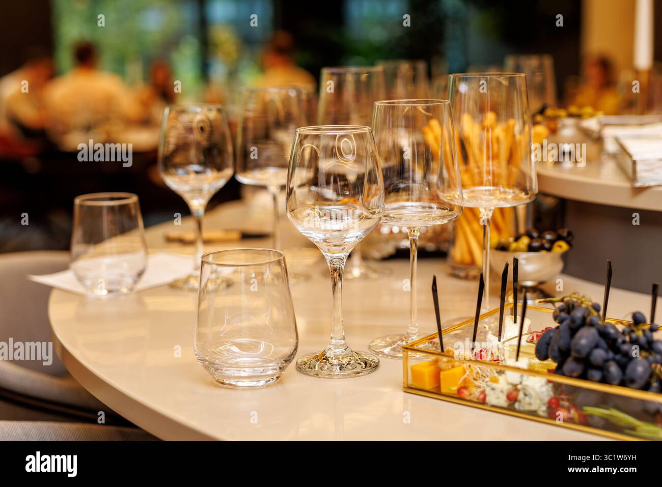 Wine tasting setup with clear glasses and light snacks on a white round ...