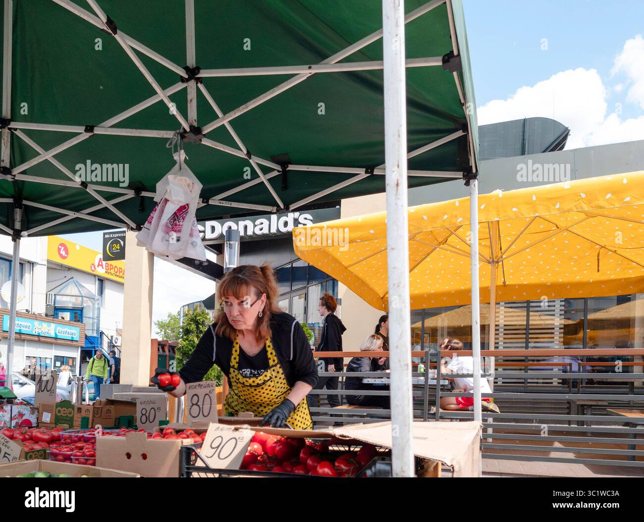 Kyiv, Ukraine - 19th July, 2025: Saleswoman arranging tomatoes at a ...