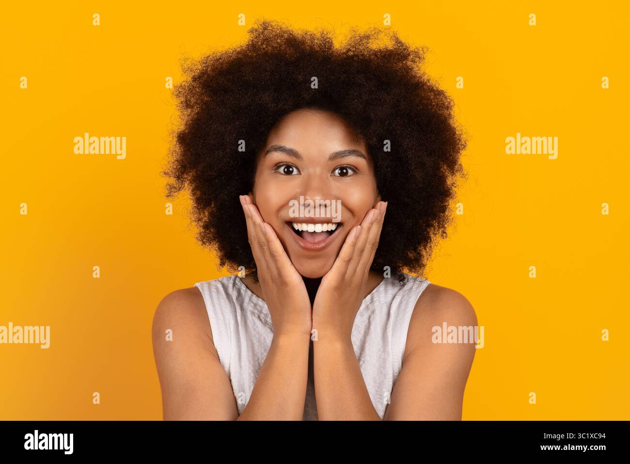 Surprised and delighted young black woman touching face with hands ...