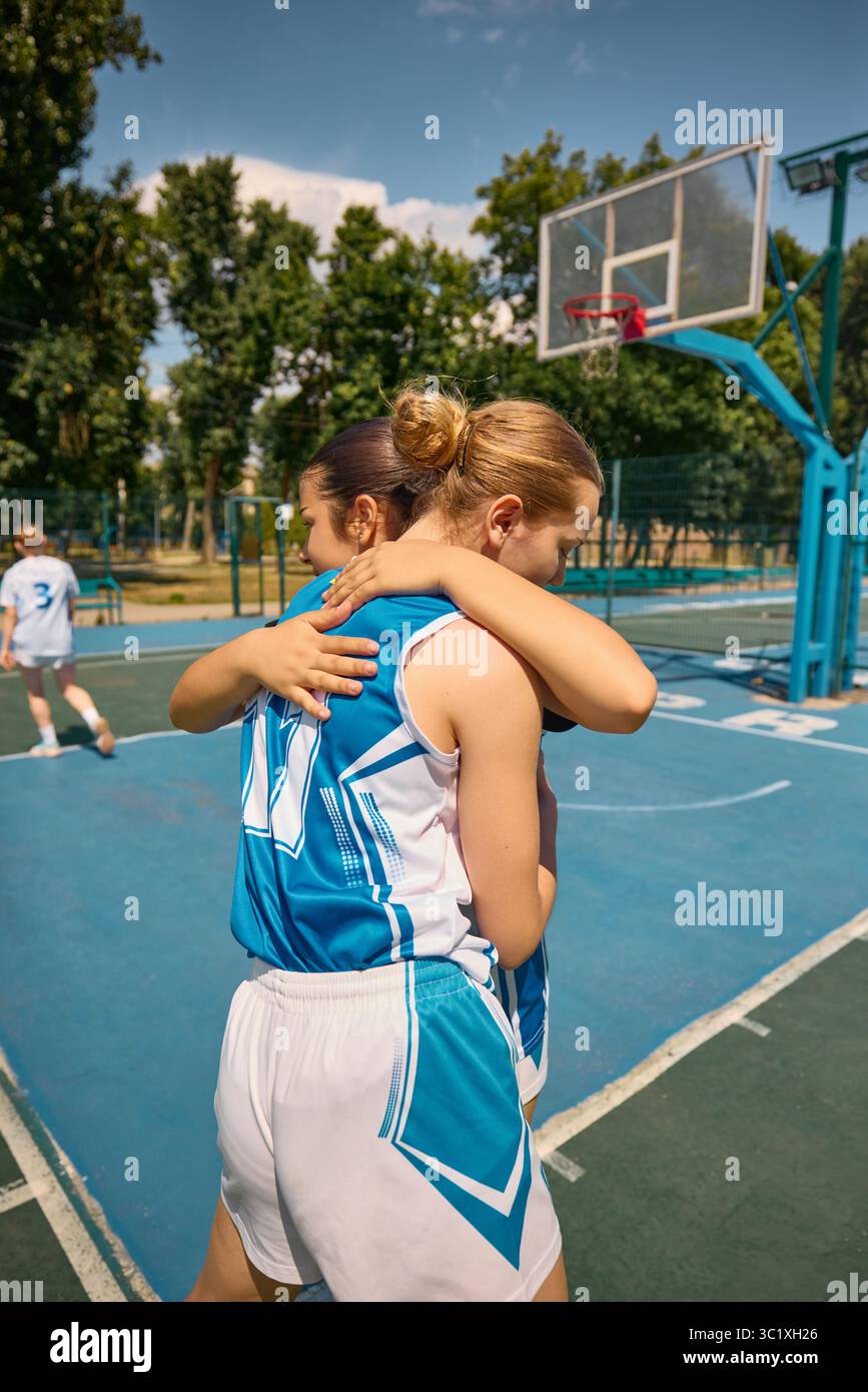 Team members hugging on an open-air basketball court during summer ...