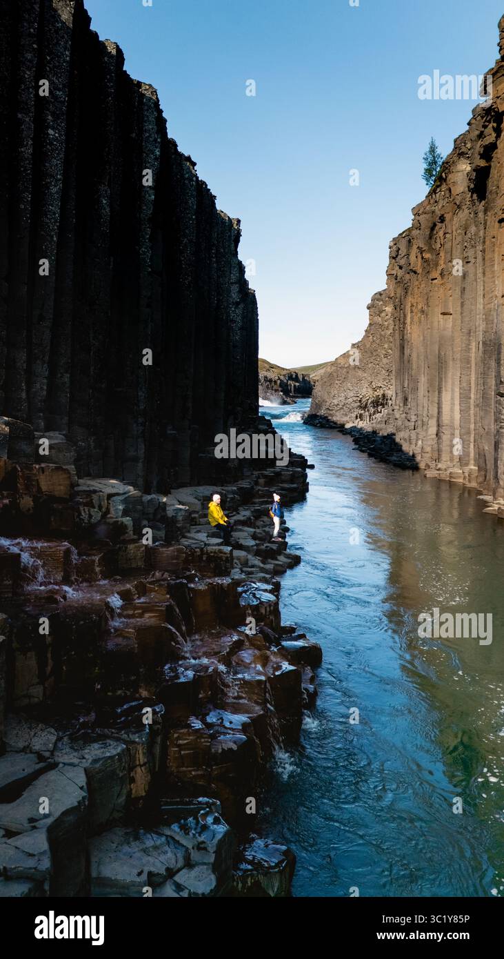 Vibrant adventurers explore the stunning Studlagil Canyon, surrounded ...
