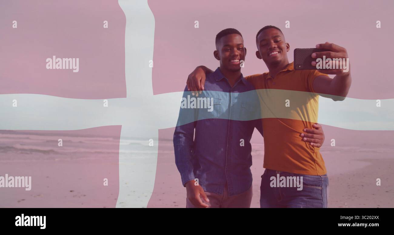 Taking selfie with smartphone, two men in orange polo on sandy beach ...