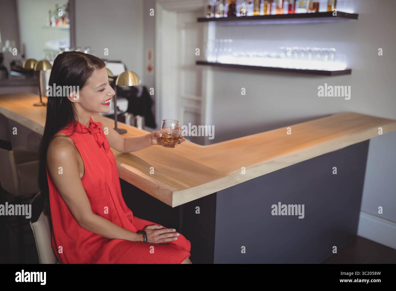Native American woman sipping drink from short glass at bar with ...