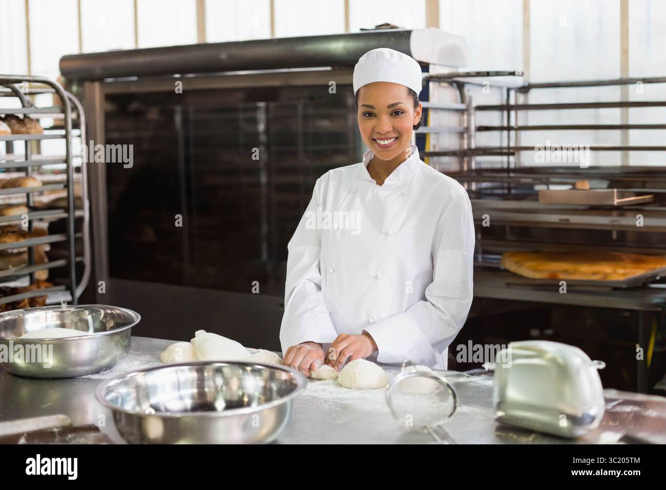 African American woman kneading dough on bakery prep table with ...