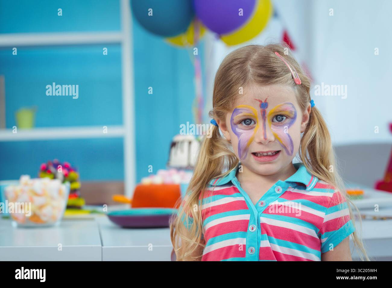Colorful balloons are floating above table with orange-iced cake ...