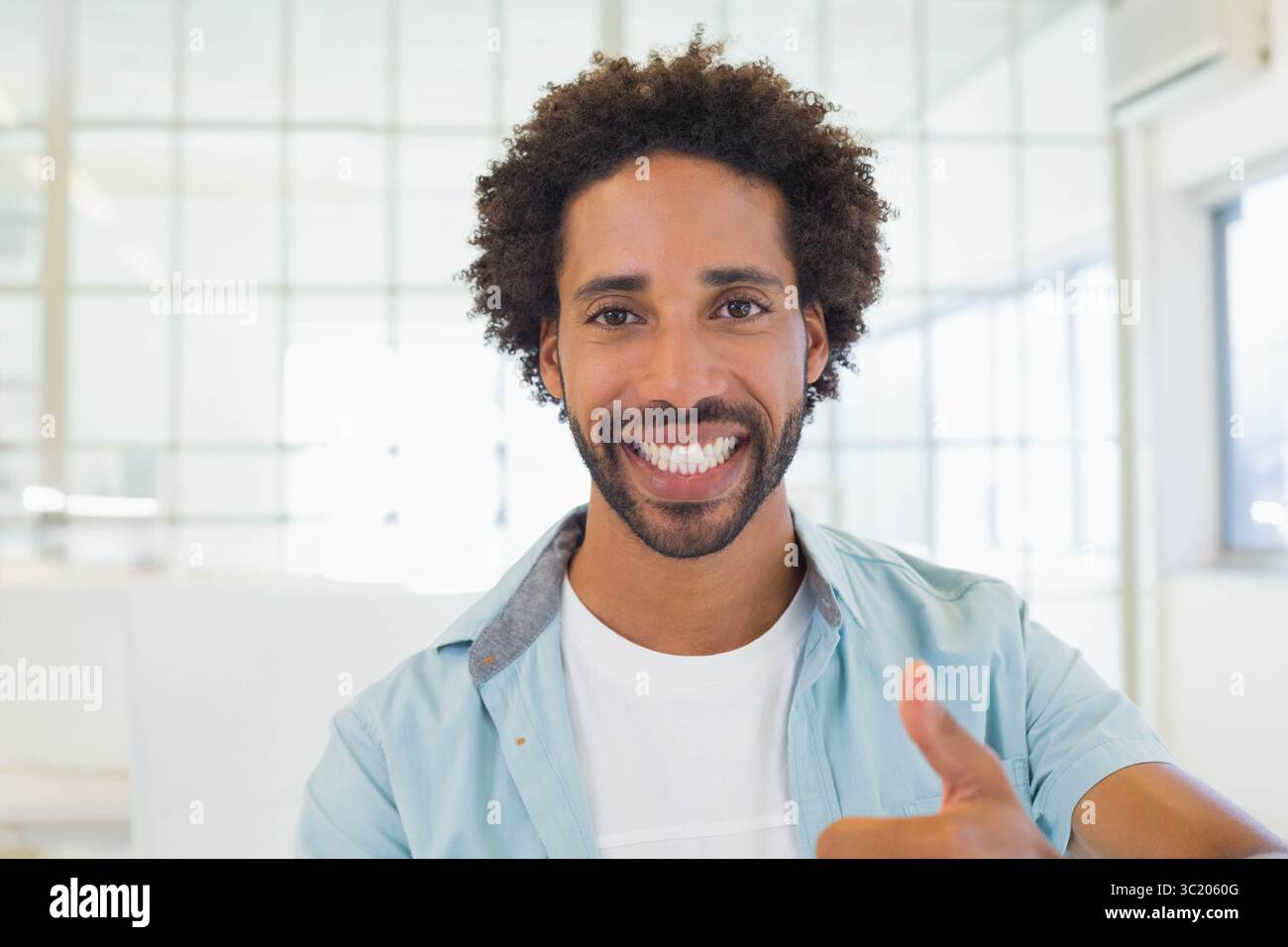 Mid adult African American man standing in modern office by windows ...