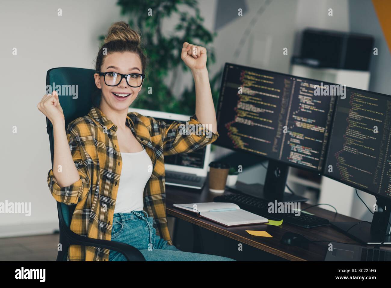 Excited female programmer celebrating success while coding at her desk ...