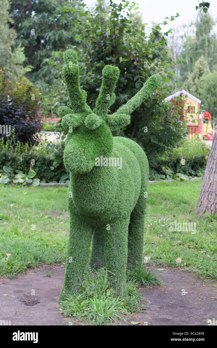 Green topiary deer sculpture in city park. Creative landscape design ...