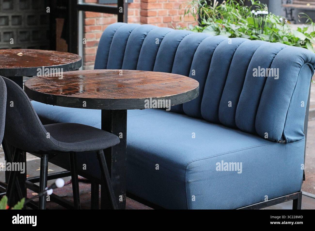 Outdoor seating area with round wooden table and soft blue couch on a ...