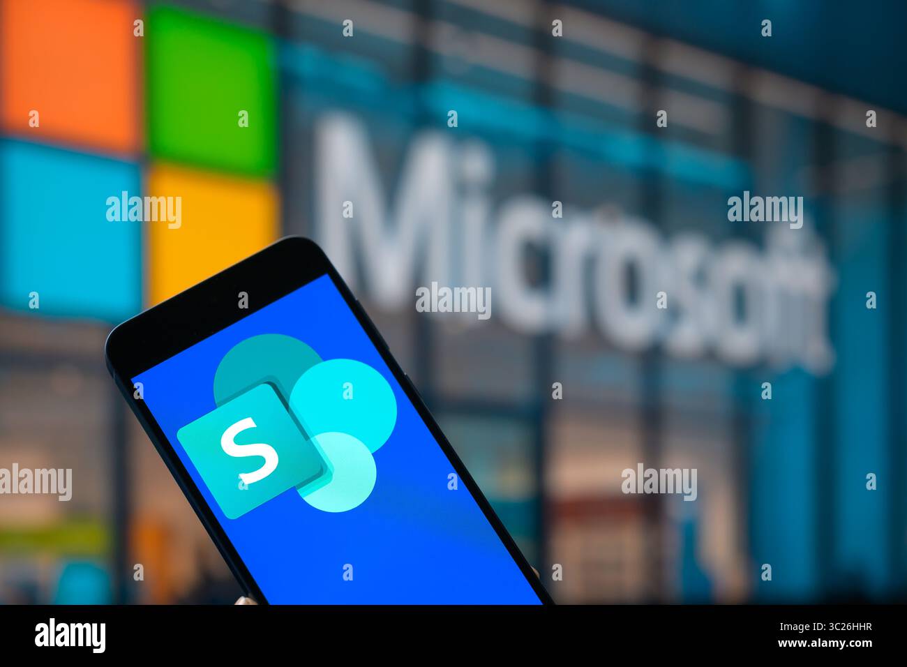 The SharePoint logo is being displayed on a mobile phone with Microsoft ...