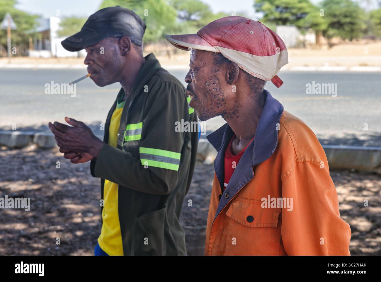 african village township, two workers smoking waiting at the bus stop ...
