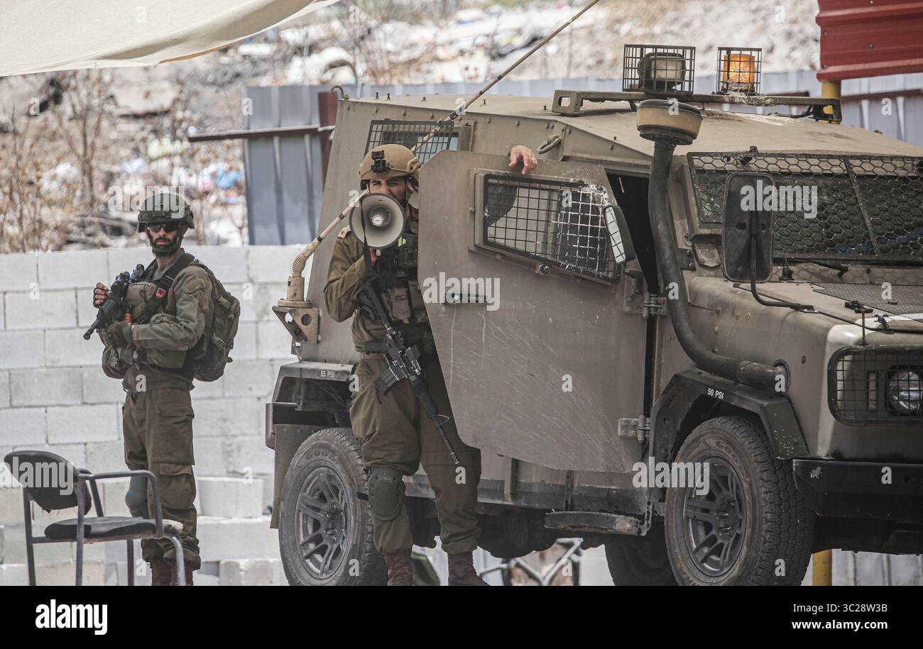 An Israeli soldier speaks into a megaphone during a raid on the city to ...
