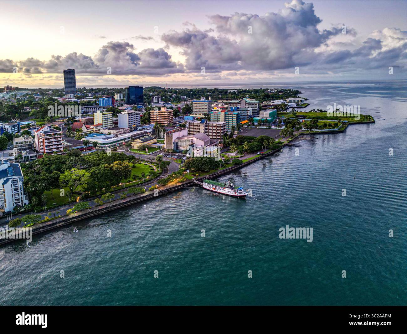 Stunning aerial of Suva City at sunrise, with lush greenery and a ...