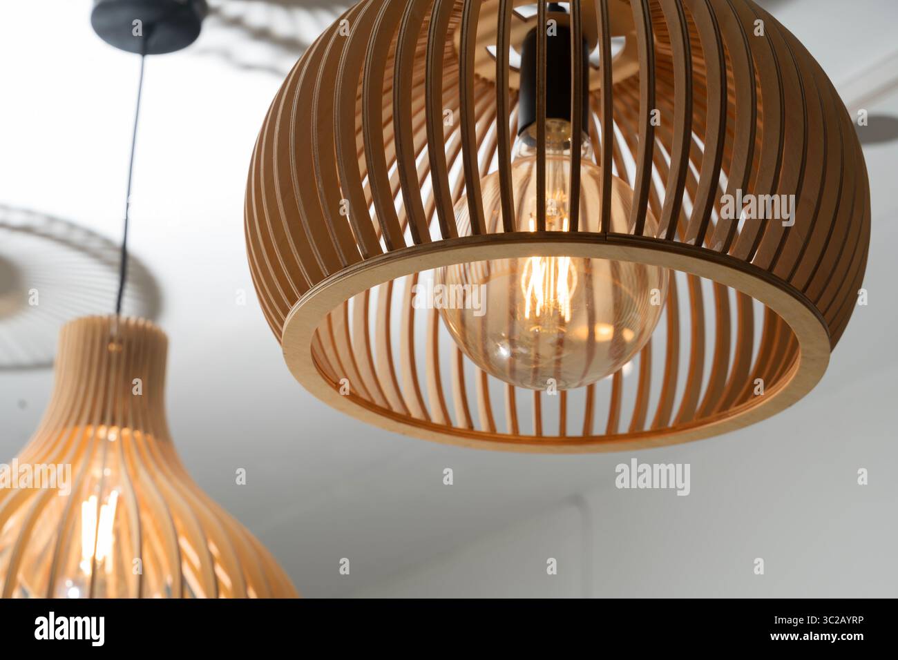 Close up view of glowing filament bulb inside modern wooden pendant ...