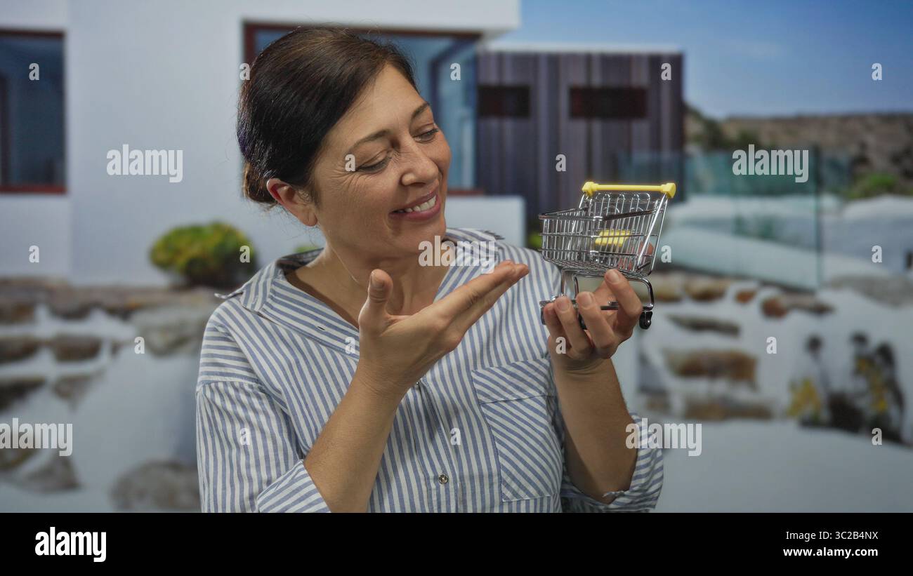 Woman holds miniature shopping cart at house entrance outdoors with ...