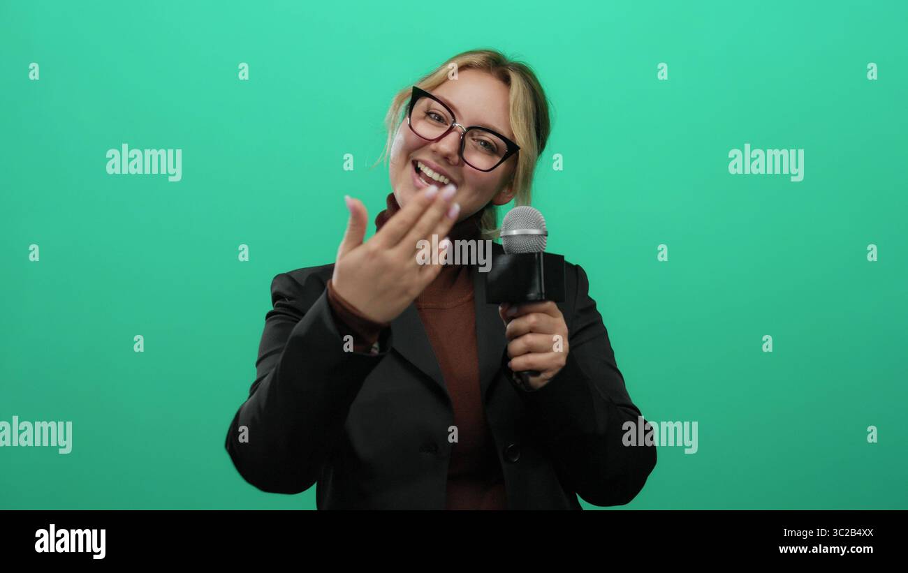 Woman reporter gesturing with a microphone against isolated green ...