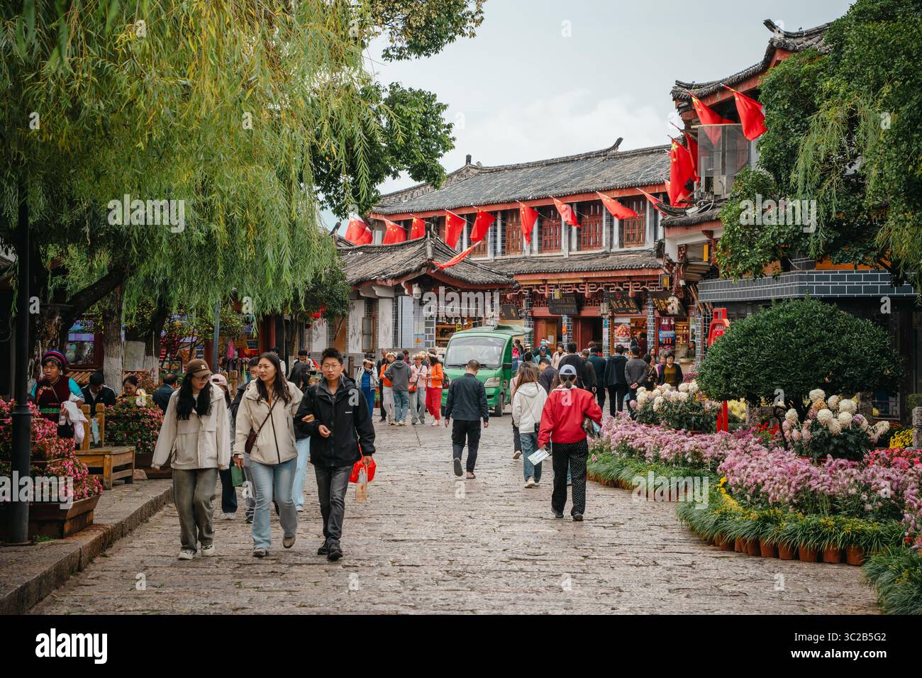 Lijiang, China - Oct 23,2024: People walk between wooden storefronts ...