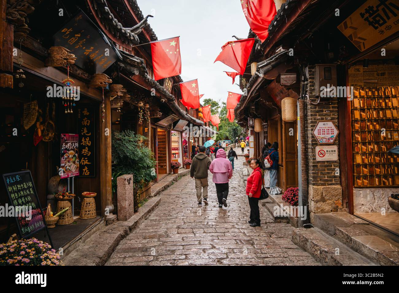 Lijiang, China - Oct 23,2024: People walk between wooden storefronts ...