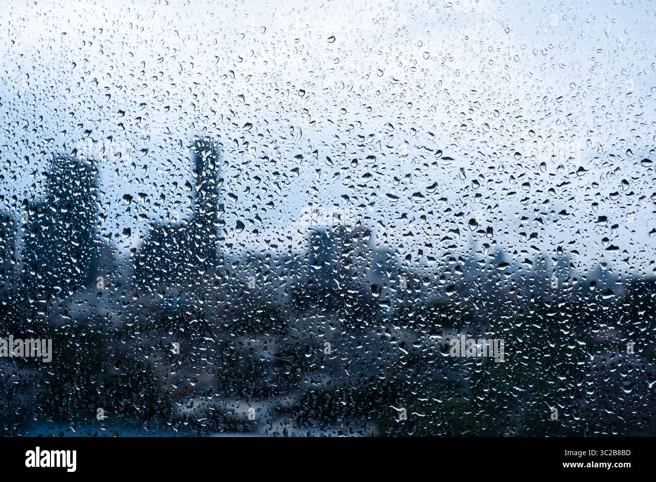 Raindrops on glass with soft city silhouette background Stock Photo - Alamy