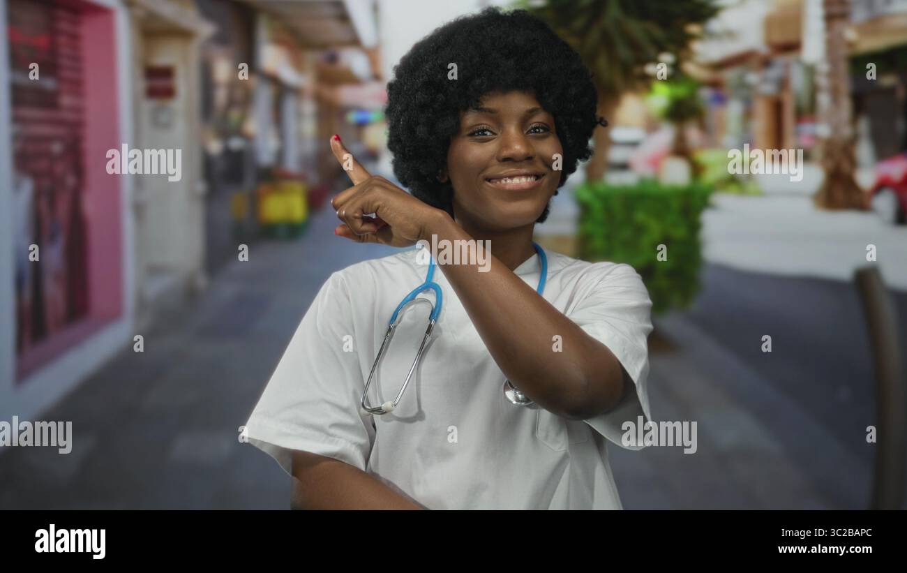Young african american woman doctor with stethoscope points finger on ...