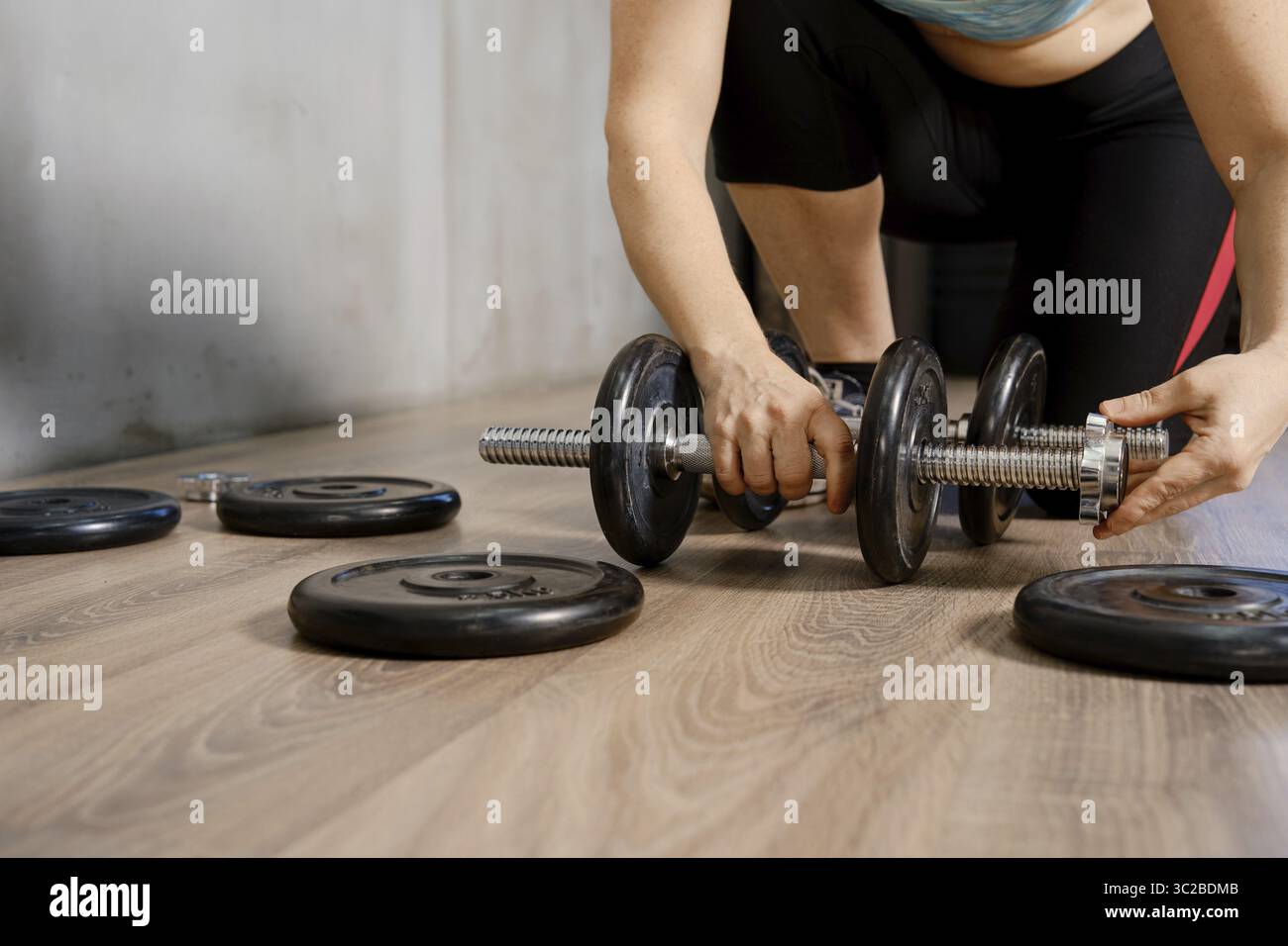 A person is adjusting weights on a dumbbell while preparing for an ...