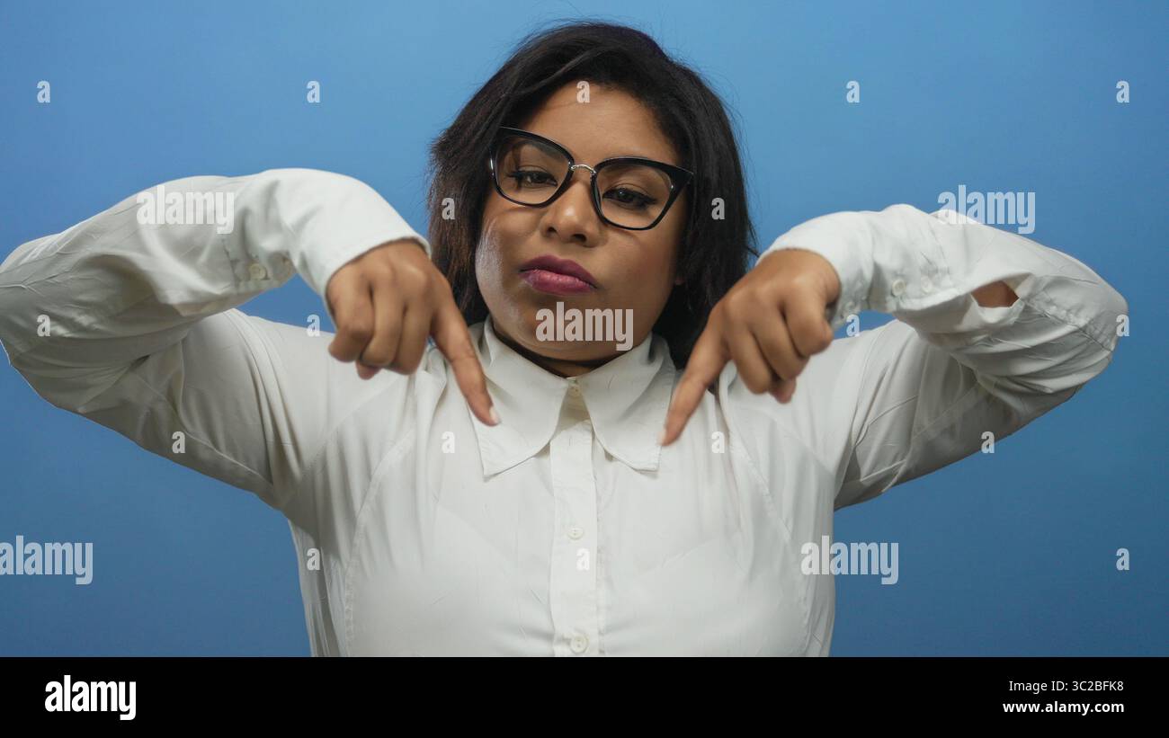 Woman pointing down with confident expression, wearing glasses and ...